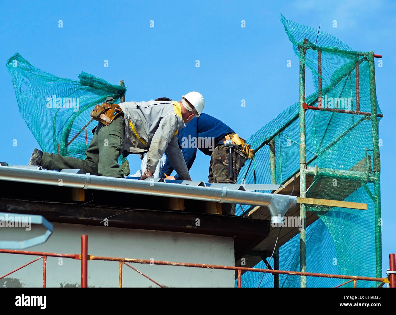 Construction workers on the roof of a building Stock Photo - Alamy