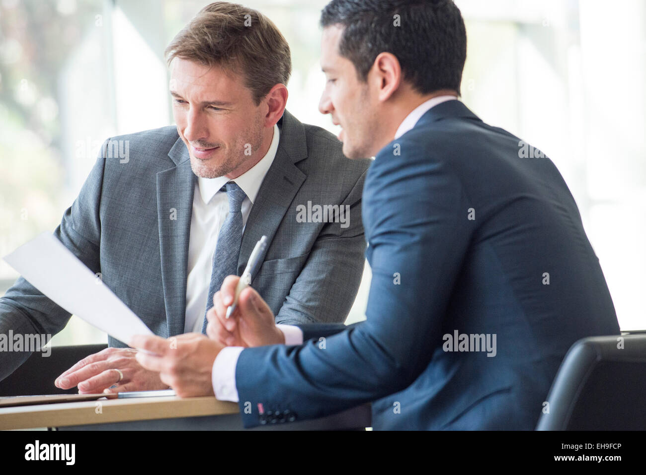 Businessmen discussing document in meeting Stock Photo - Alamy