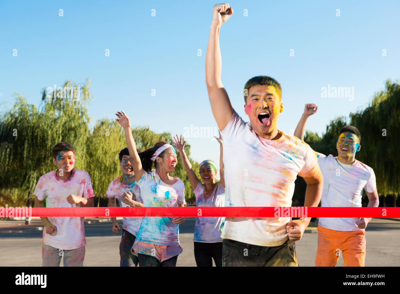 Young man crossing finishing line at The Color Run Stock Photo - Alamy