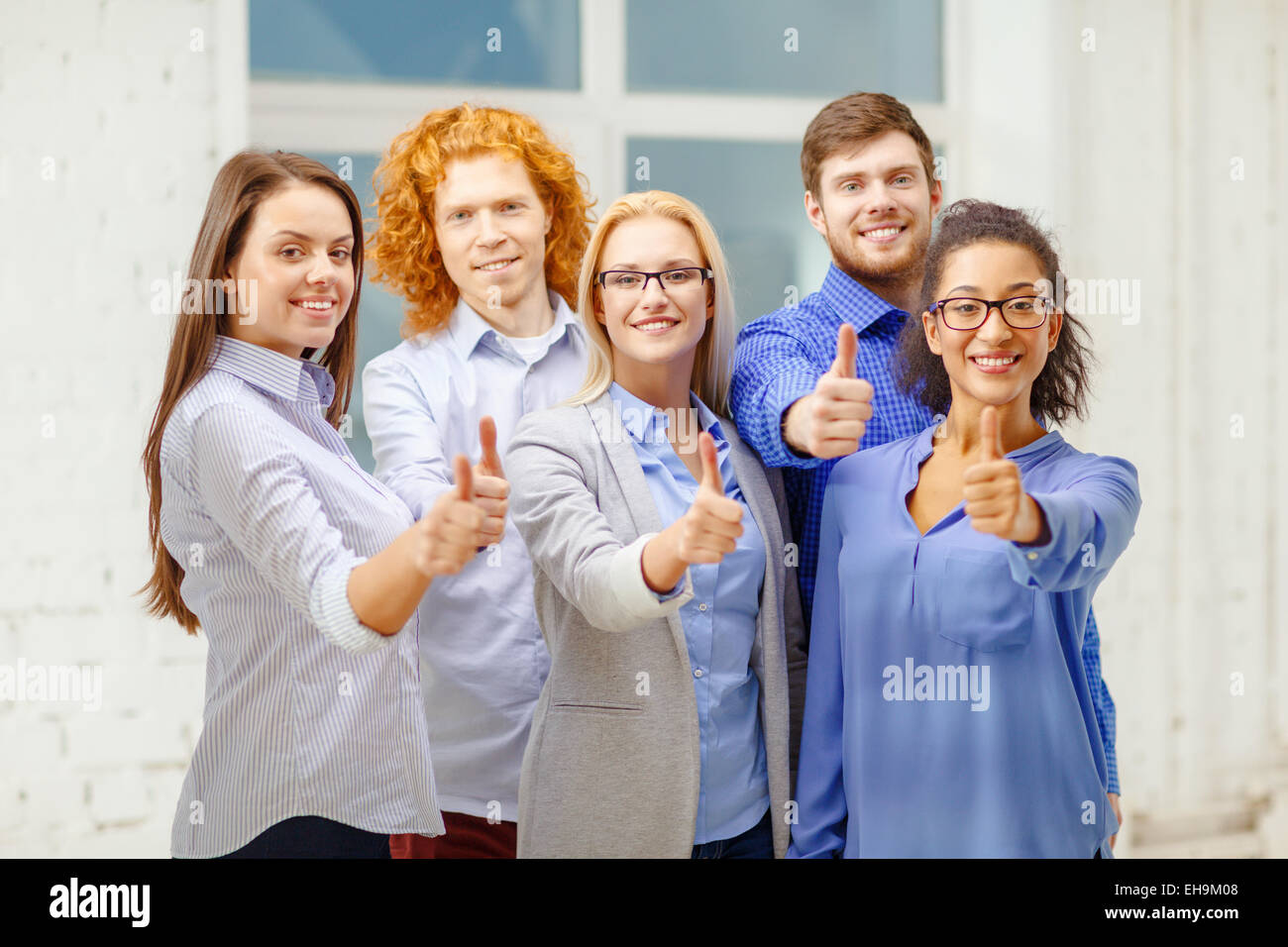 happy creative team showing thumbs up in office Stock Photo - Alamy