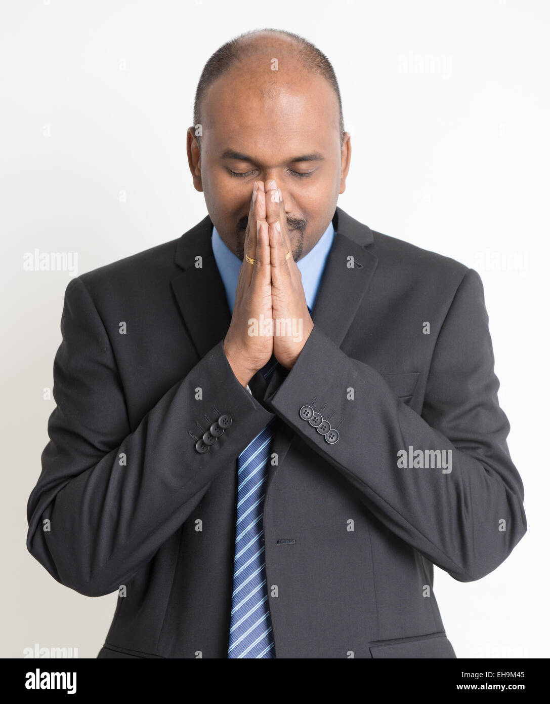 Indian businessman in praying gesture, on plain background Stock Photo ...