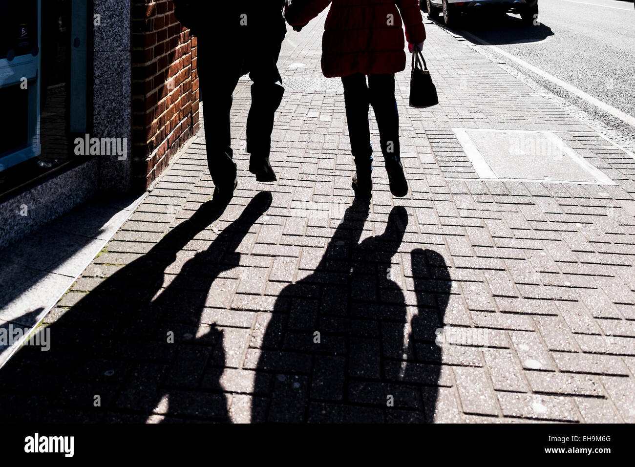 Stark shadows cast by pedestrians walking along a pavement Stock Photo ...