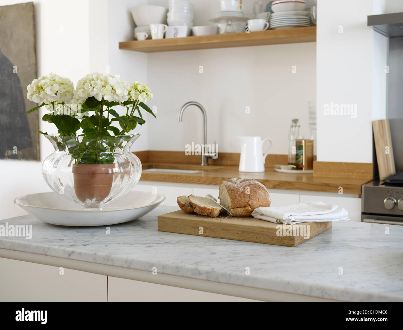 Marble work surface with bread and flower bowl in front of kitchen sink ...