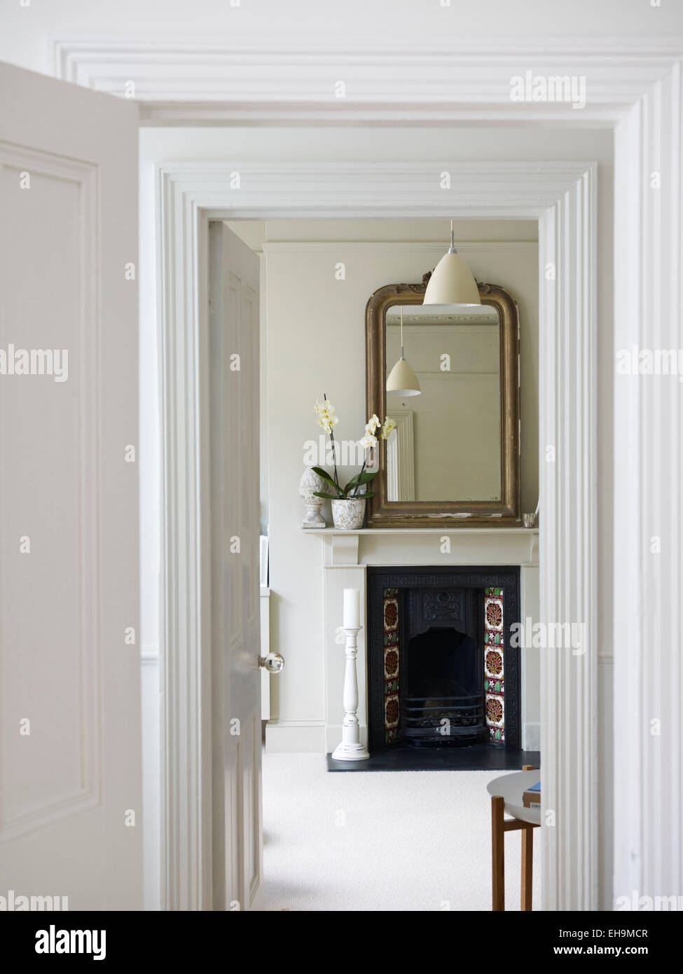 View through white door into room with fireplace and mirror ...