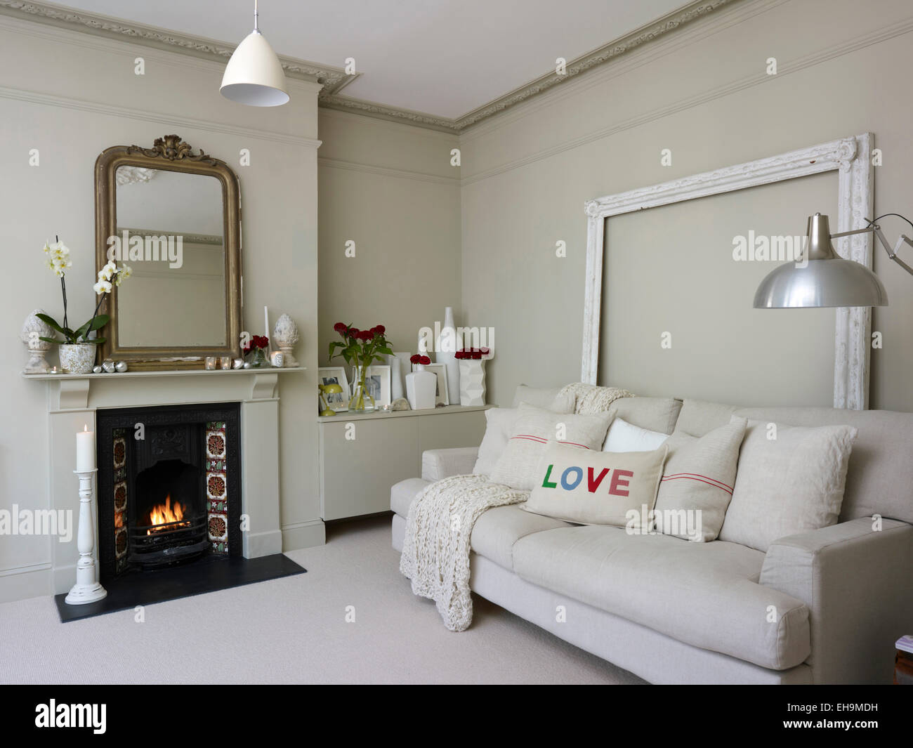 White sofa in front of open fire in white sitting room, residential ...