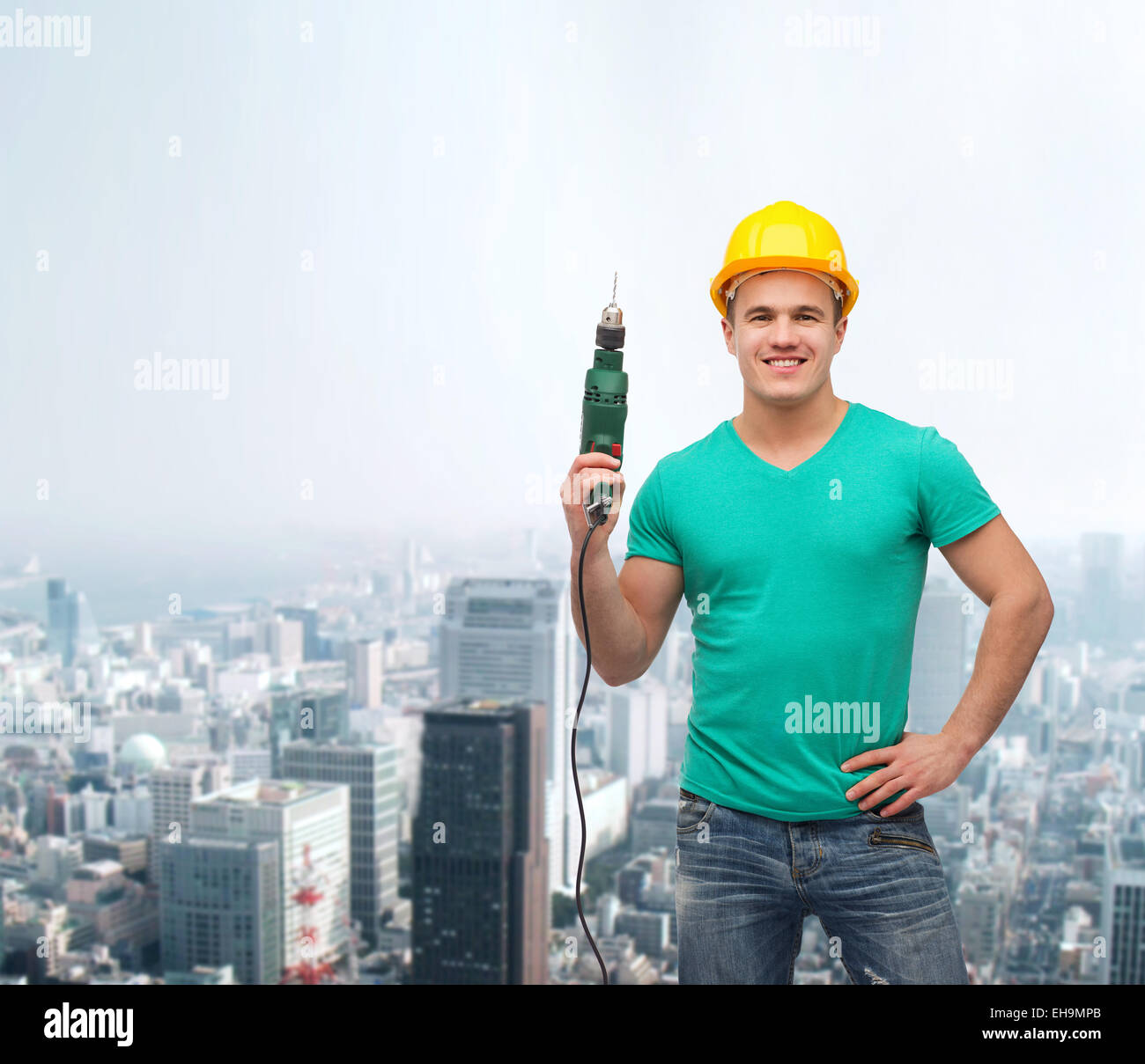 smiling manual worker in helmet with drill machine Stock Photo - Alamy