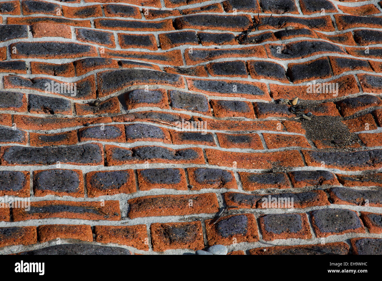 A red brick wall worn by the sea into a wave pattern at Tonfannau on ...