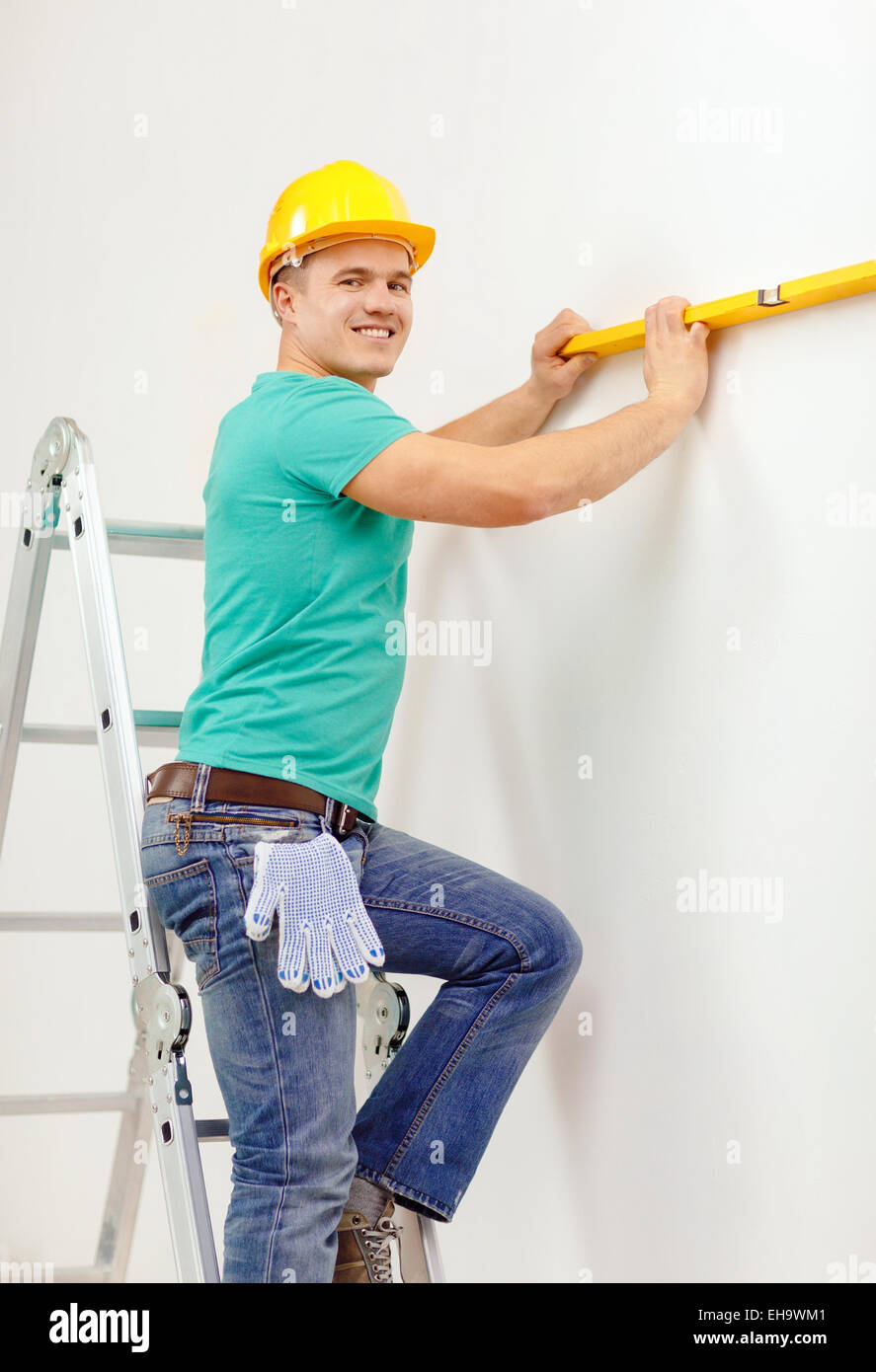 smiling man building using spirit level to measure Stock Photo - Alamy