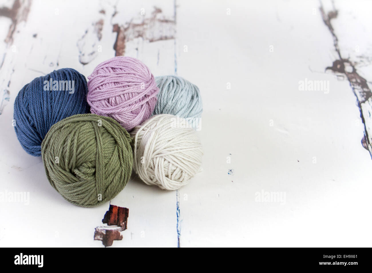Balls of wool on white distressed wood background Stock Photo - Alamy