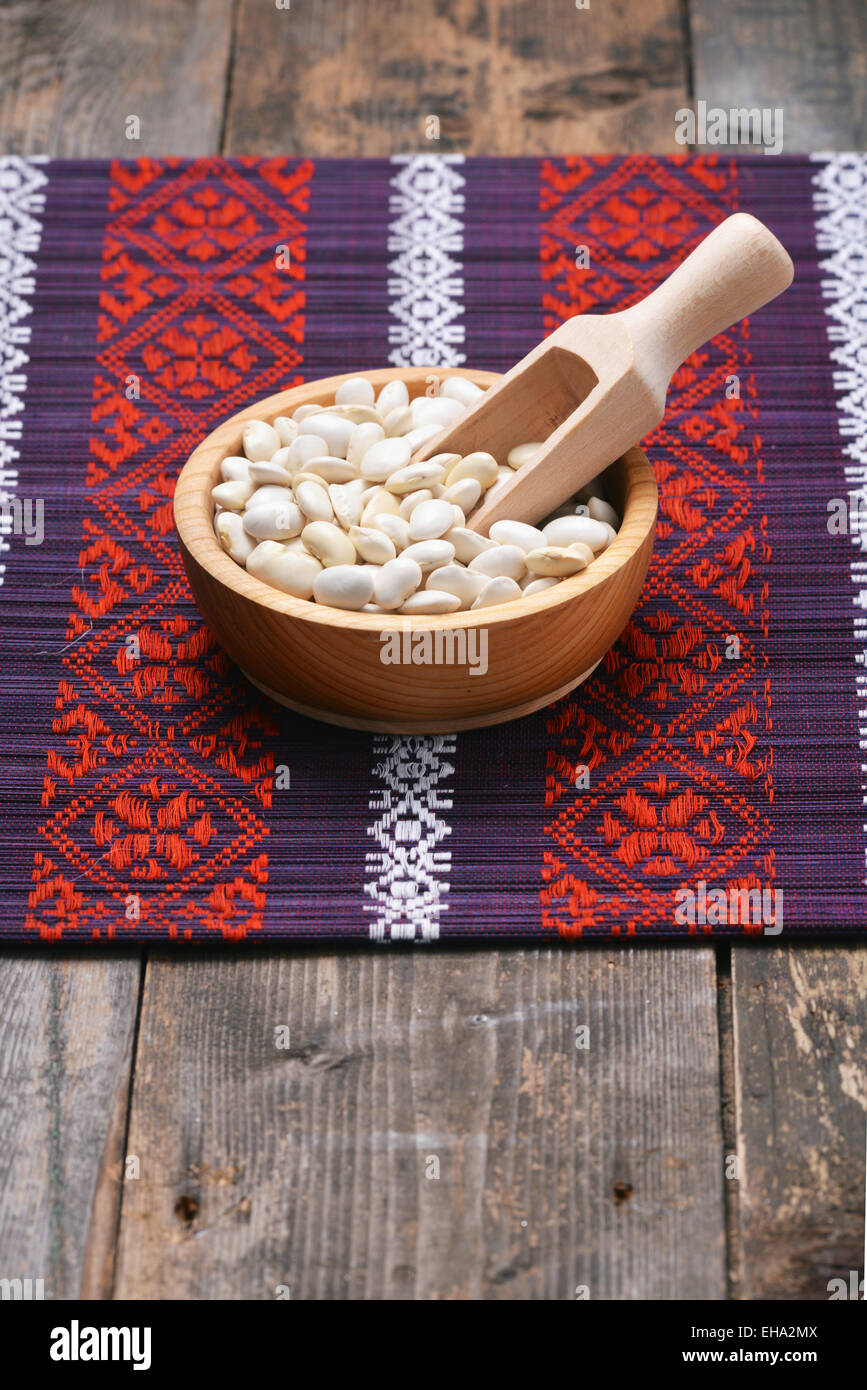 white beans in a wooden bowl on the background of the Ukrainian pattern ...