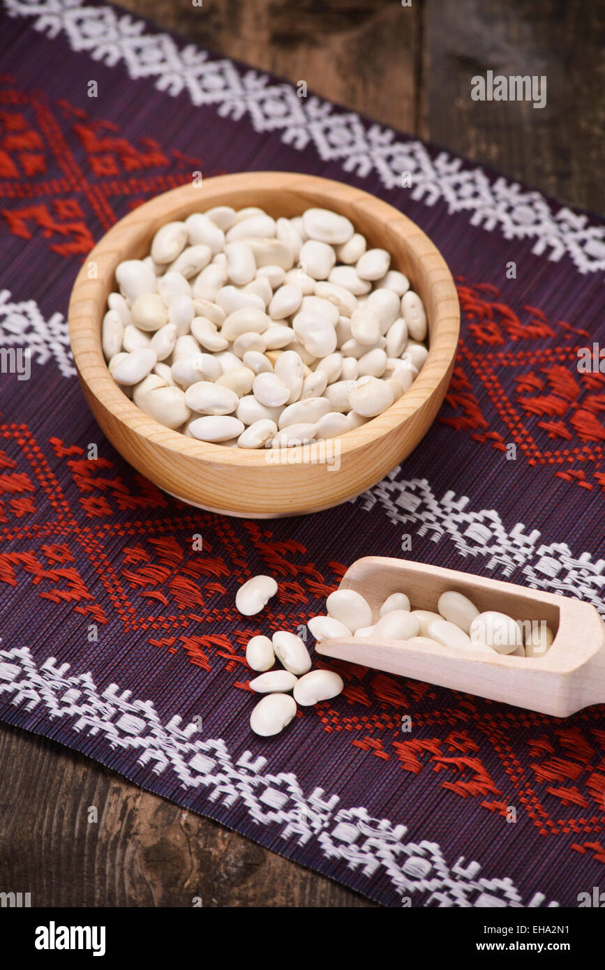 white beans in a wooden bowl on the background of the Ukrainian pattern ...
