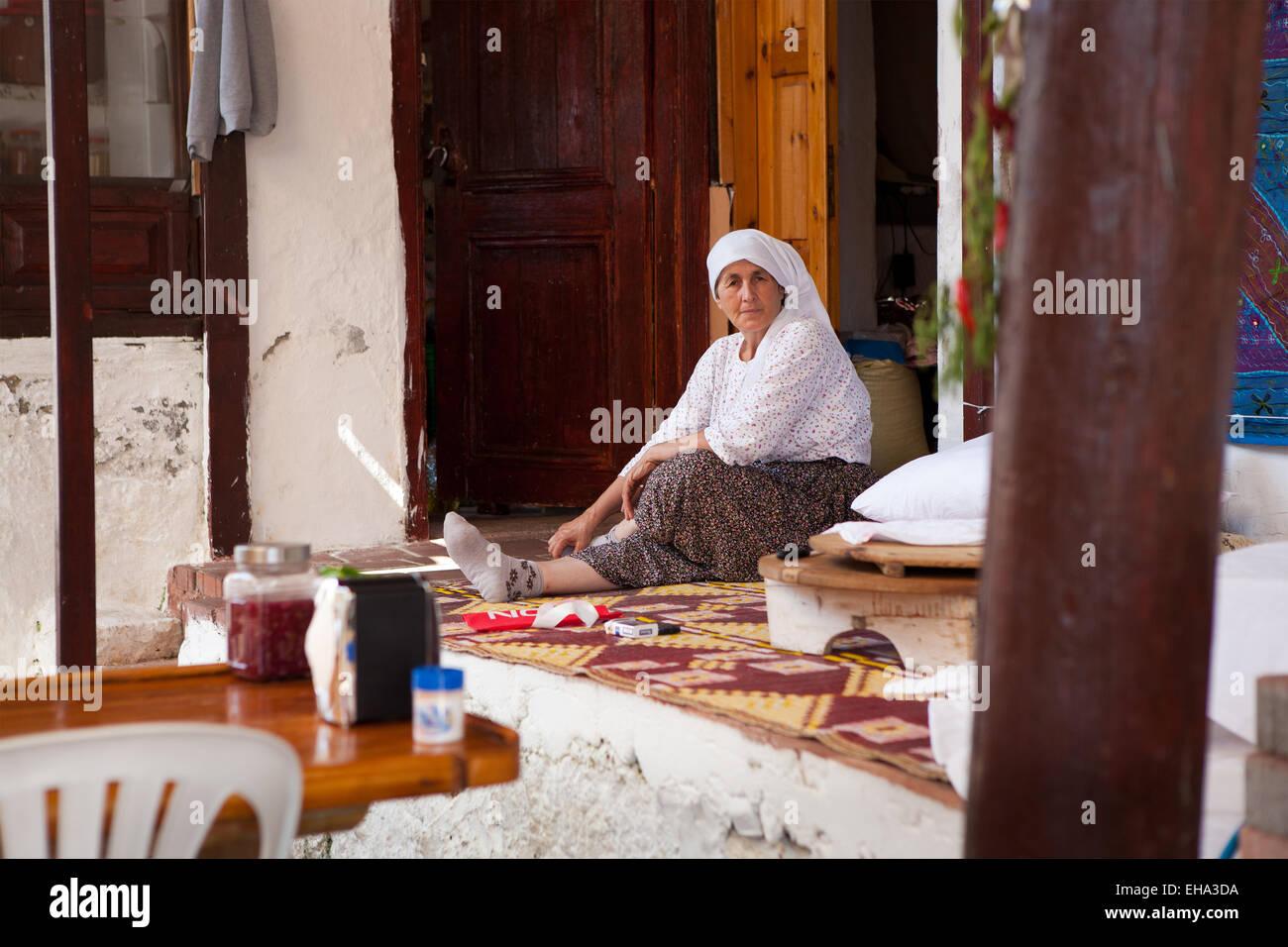 Portrait of a Turkish woman with headscarf at her porch in a small ...