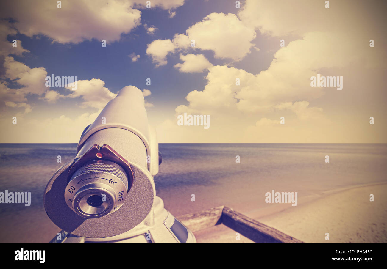 Retro toned picture of telescope on a beach pointed at beautiful sky ...