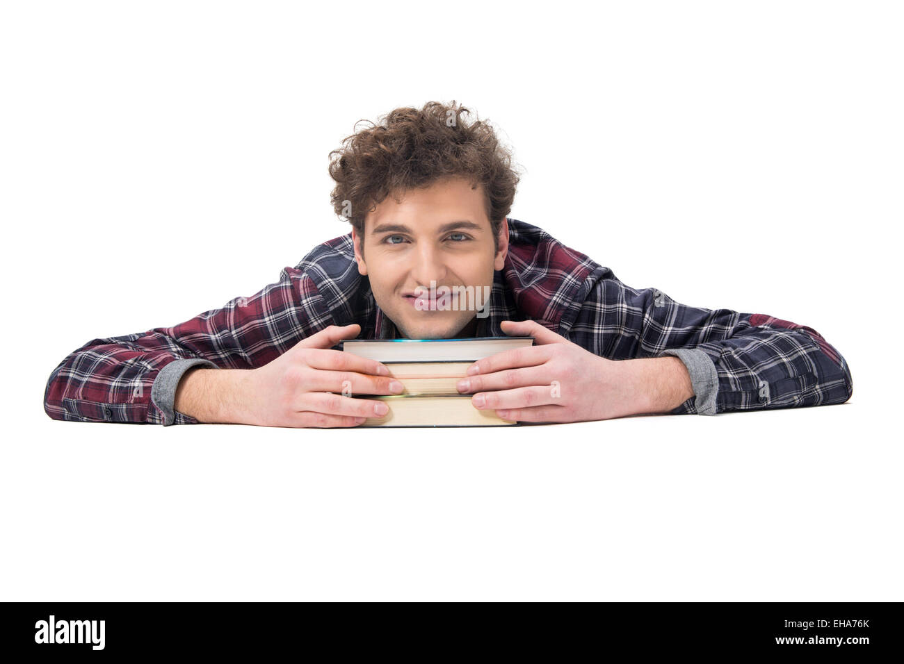 Smiling young man lying on the table with books Stock Photo - Alamy