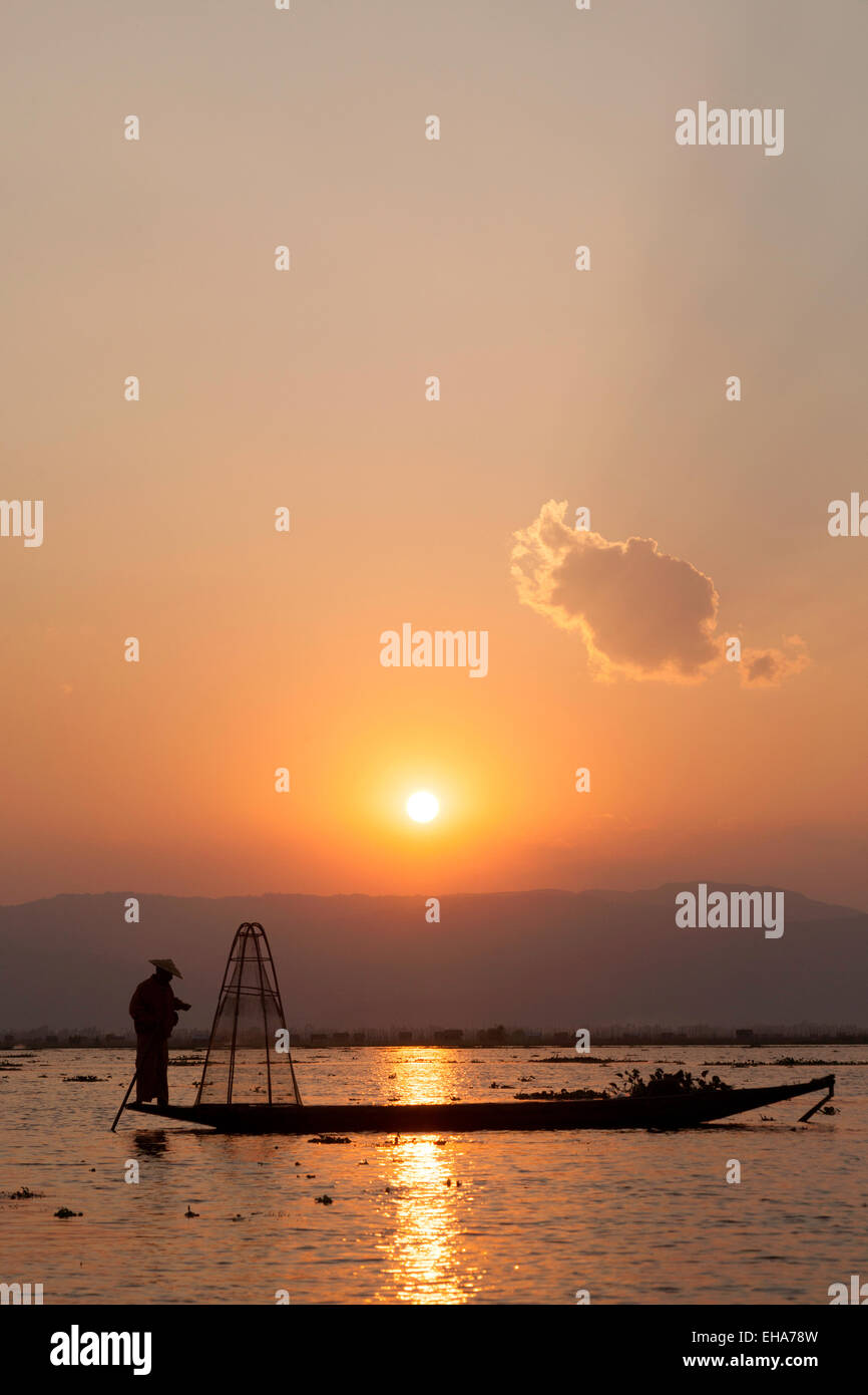 A fisherman fishing with his cone shaped net at sunset, Inle lake ...