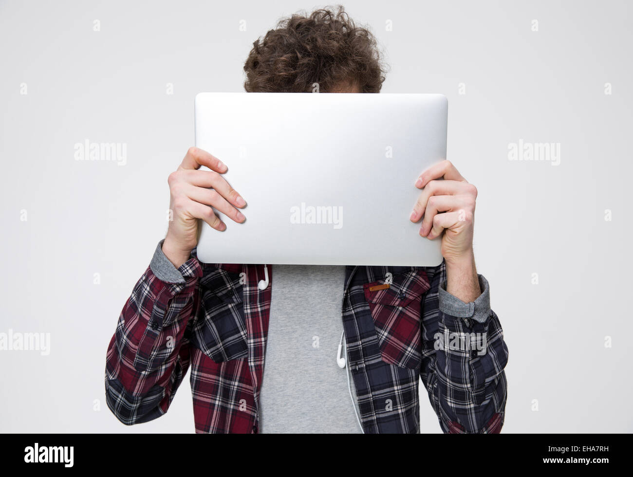 Young man covering face with laptop over gray background Stock Photo ...