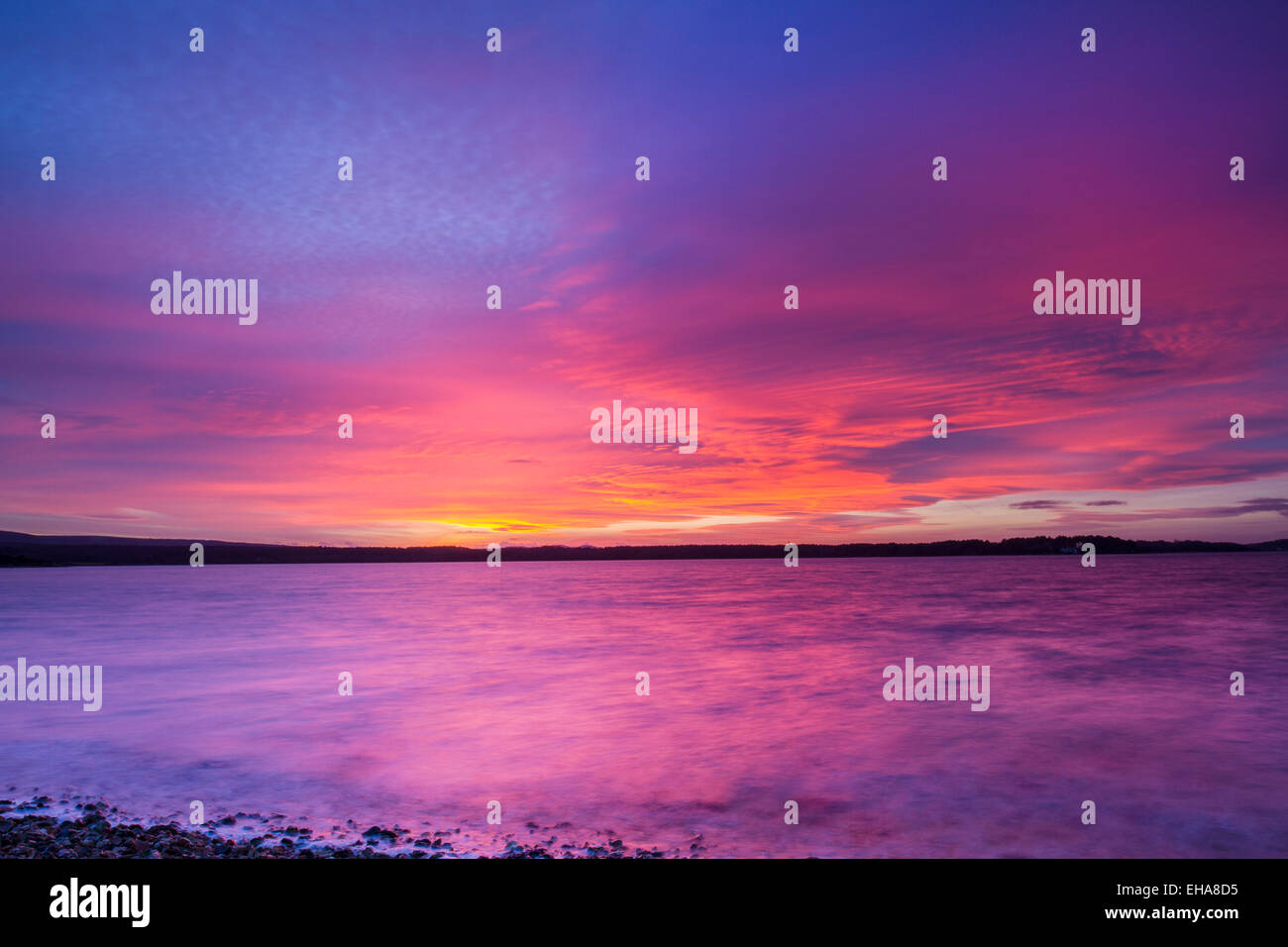 Dramatic red and pink sky over pebble bay Stock Photo - Alamy