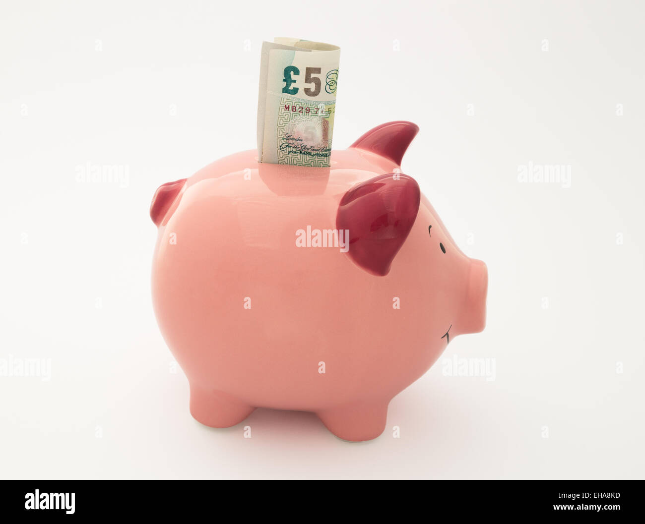 pink piggy bank with five pound (£5) note stuffed into its slot Stock ...