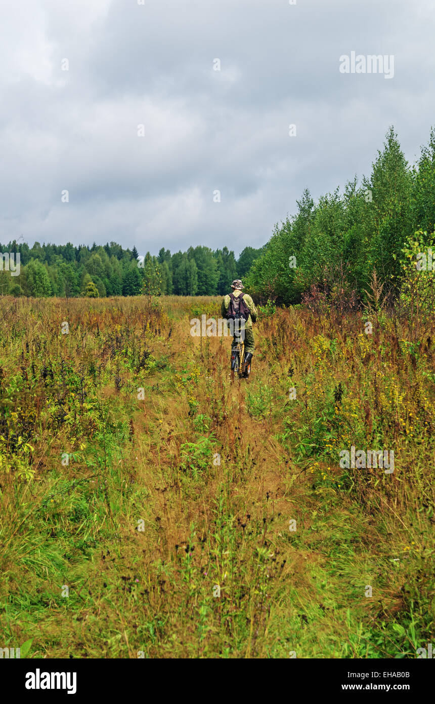 Travel by bicycle across the field densely grassed Stock Photo - Alamy