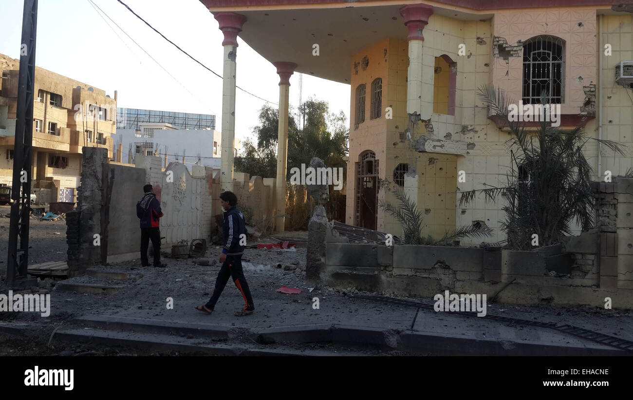 Fallujah, Iraq. 10th Mar, 2015. A man walks by a destroyed building ...