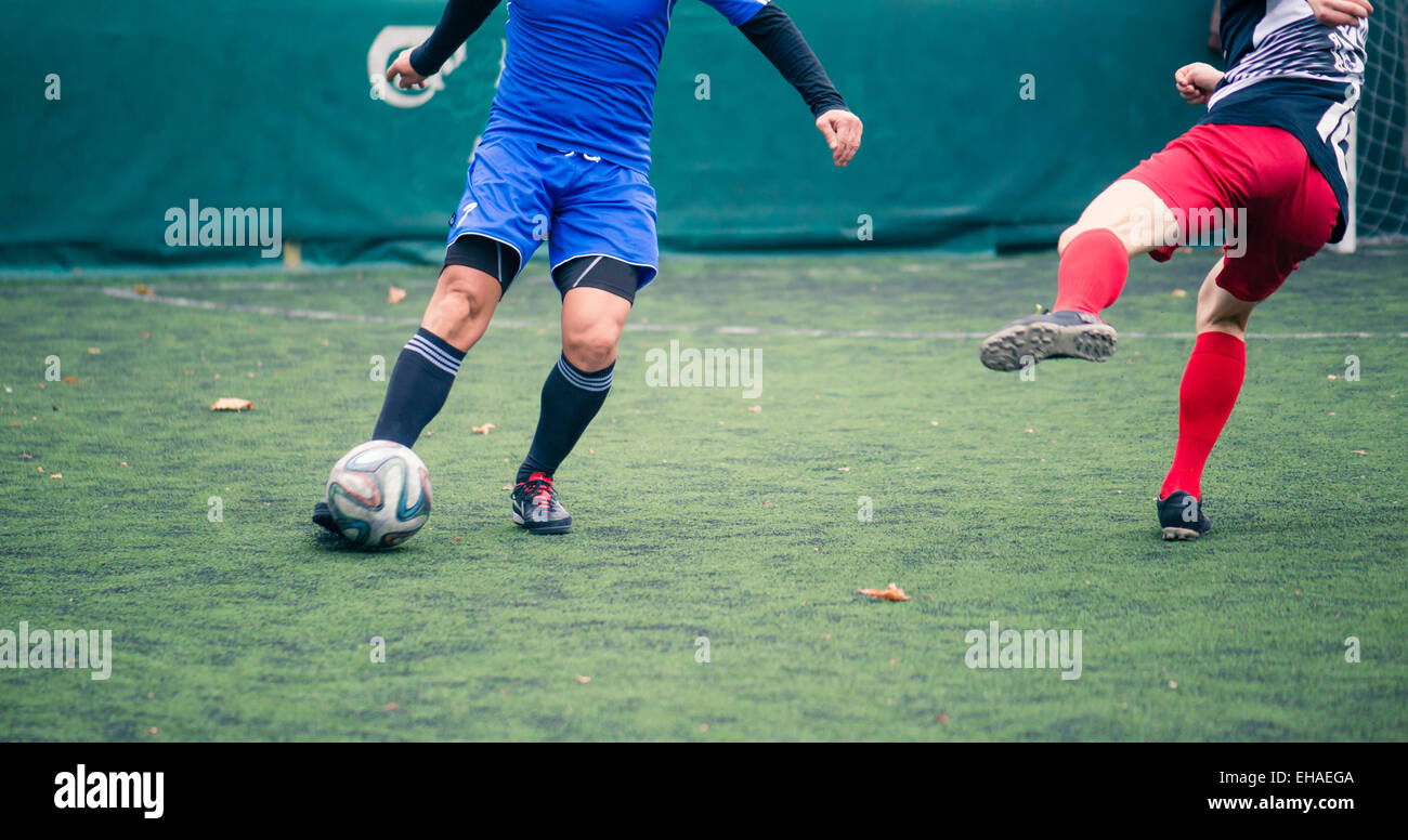 Two footballers chasing ball on grass-field during game Stock Photo - Alamy