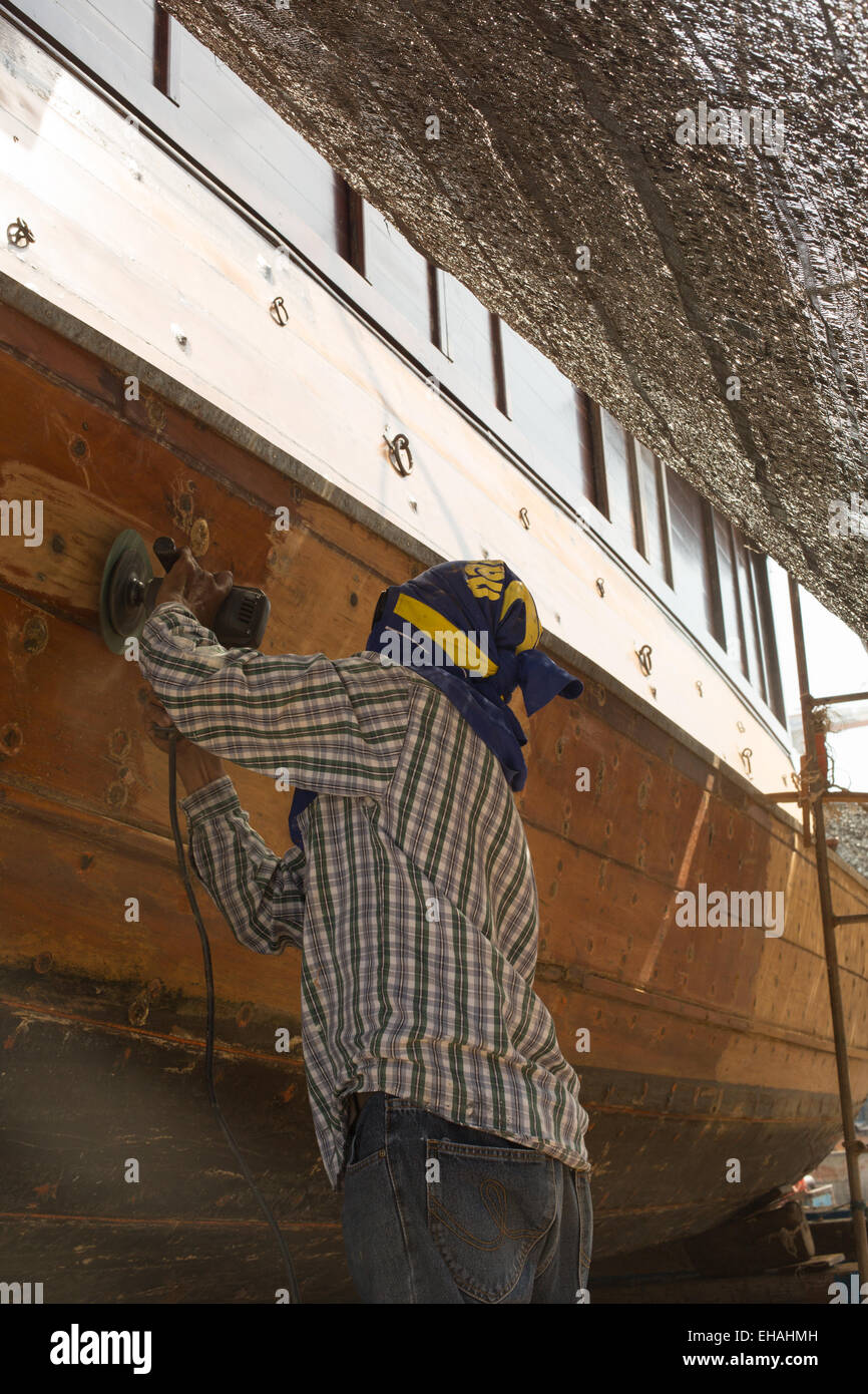 Manual worker sands down a ship exterior in a boatyard, Tha Chalom ...