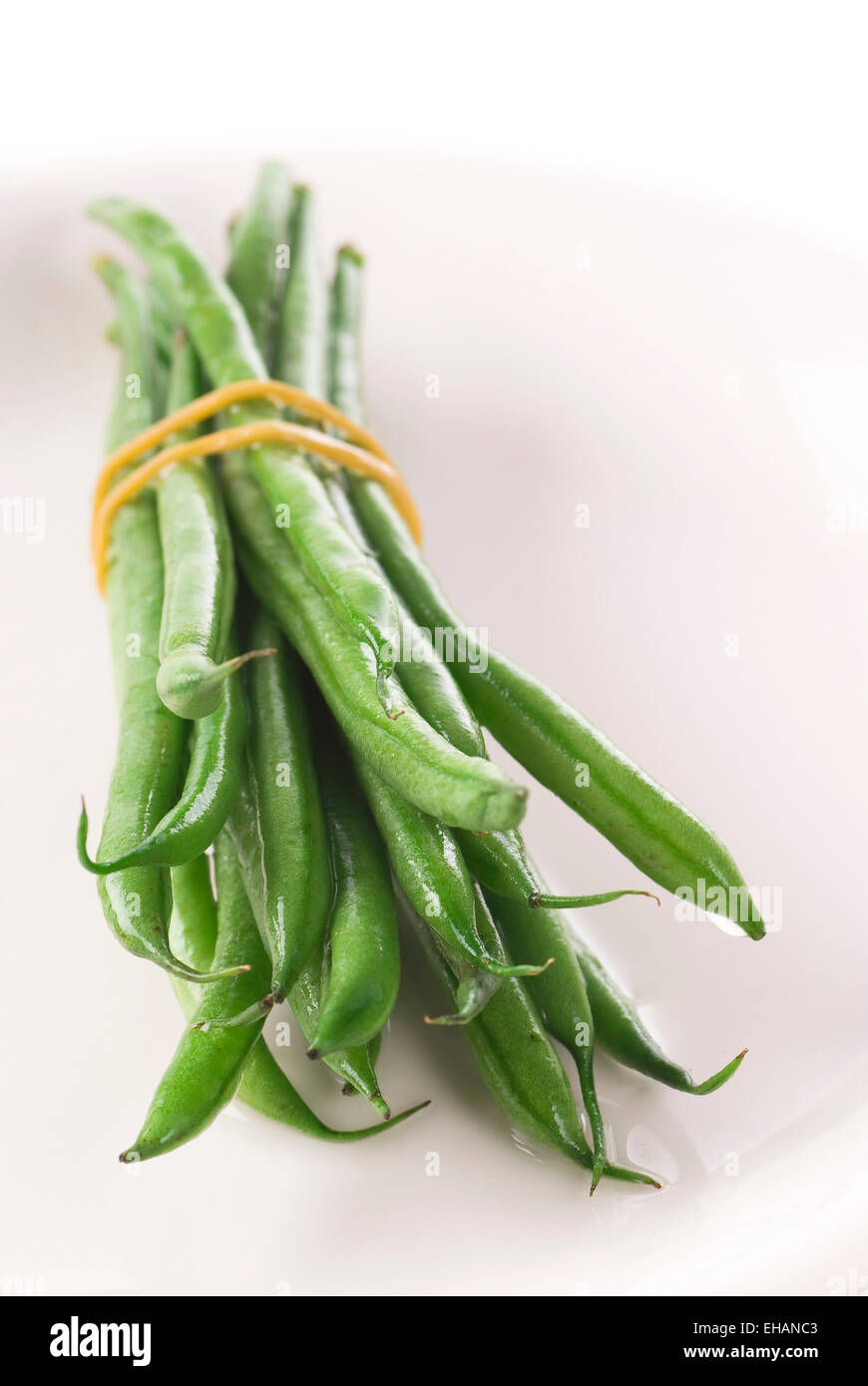 Bunch of rinsed green beans with rubber band on a plate Stock Photo - Alamy