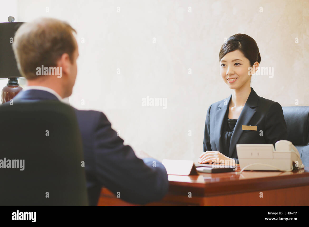Japanese female hotel concierge dealing with a customer Stock Photo - Alamy