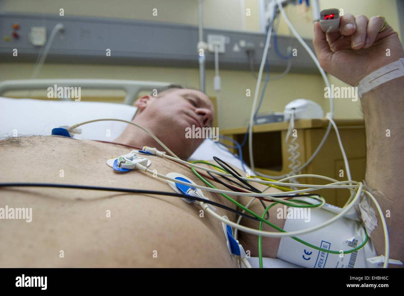 A man lies in a hospital bed with heart monitors to assess the risk of ...