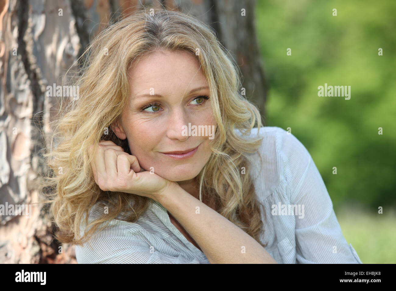 Woman smiling under tree Stock Photo - Alamy