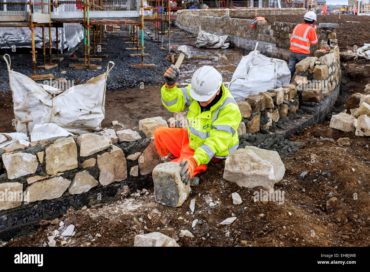 Master mason building a decorative perimeter wall of bloom sandstone on ...