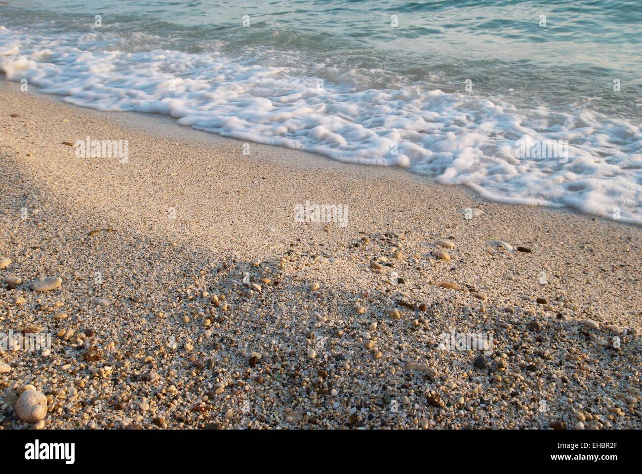 Tropical sand beach with sea waves and stones Stock Photo - Alamy