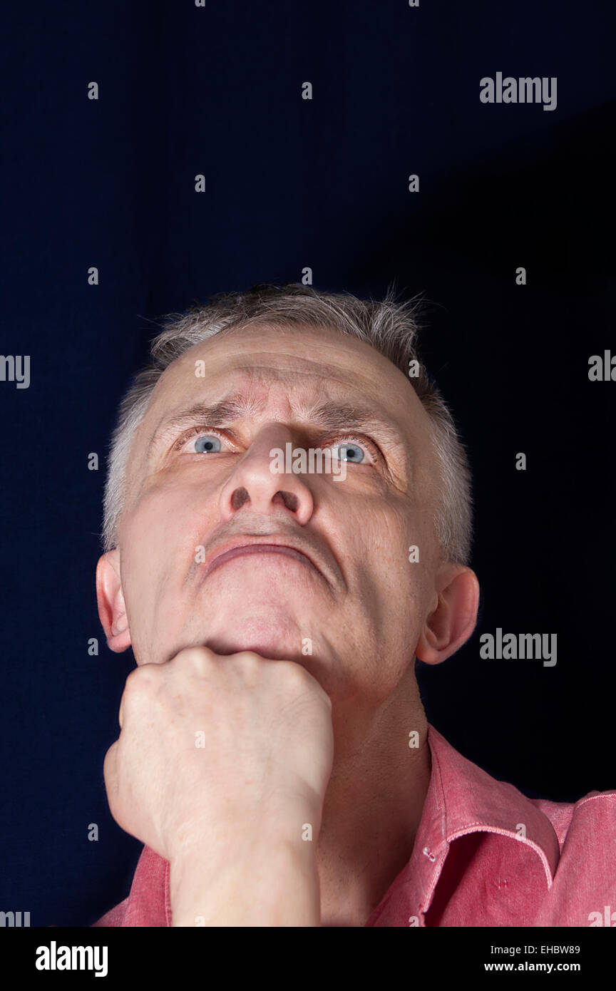 Portrait of a man with a weird look, holding one chin by hand, low ...