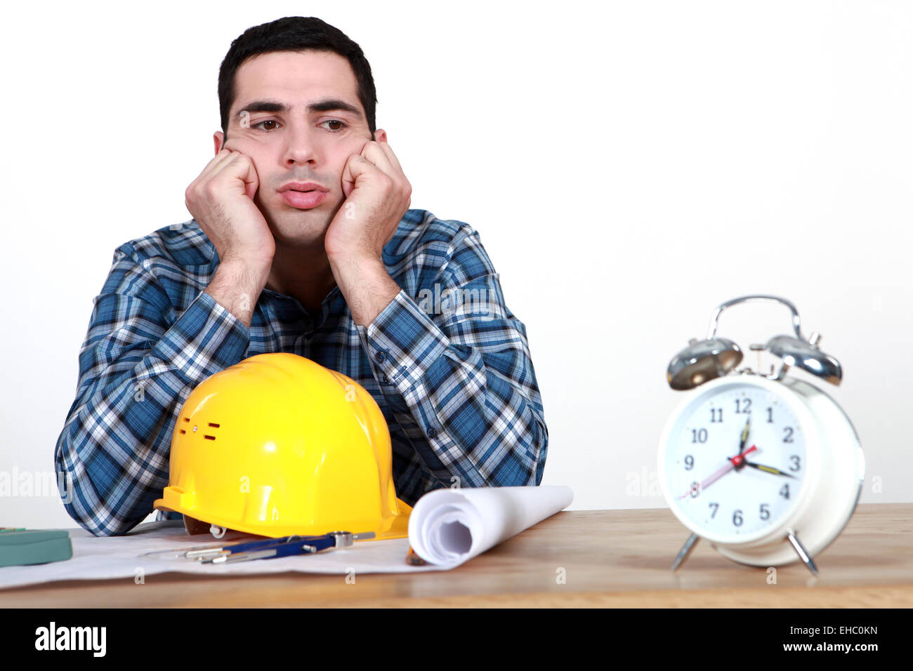 Construction worker with plans and an alarm clock Stock Photo - Alamy