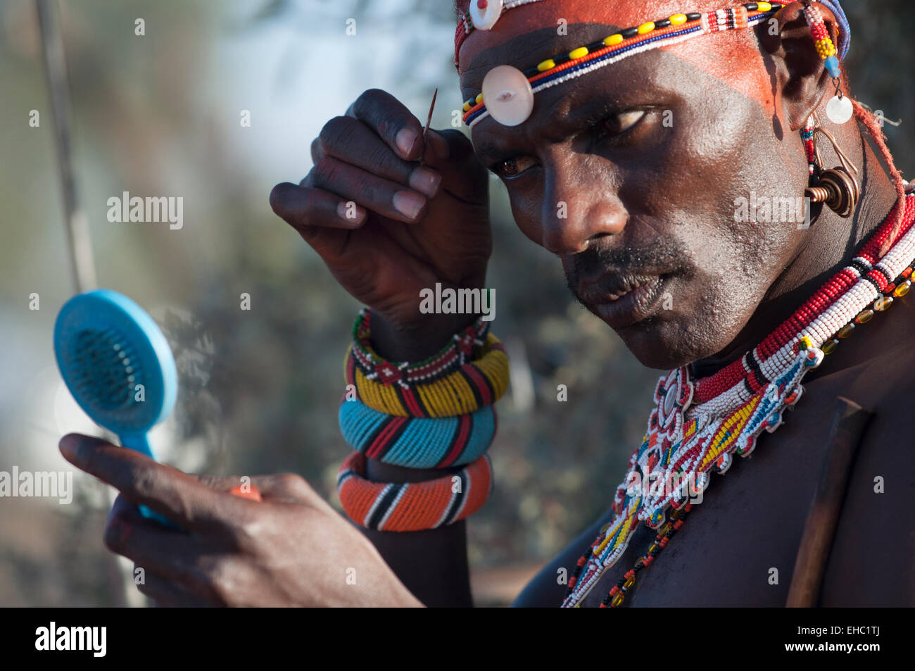 A Samburu Moran (warrior) checking his look on a small mirror, Archer's ...