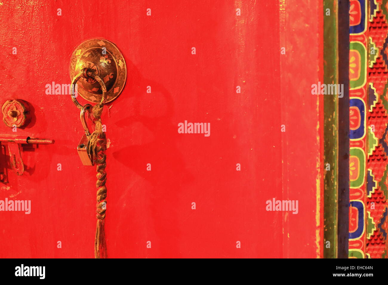 Red painted wooden door-gilded brass doorknob-braided cloth hanging ...