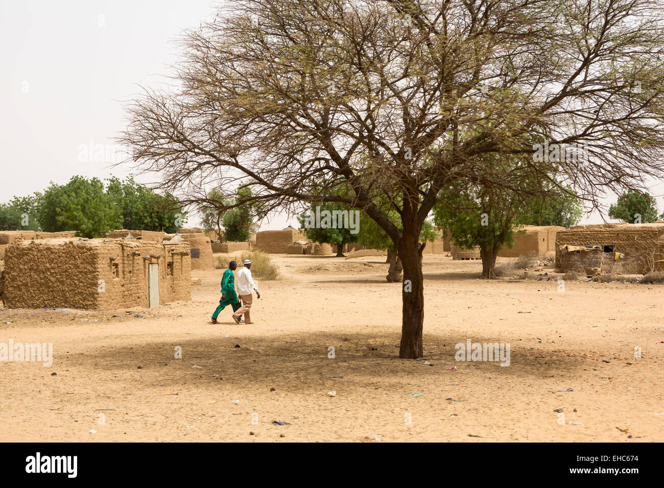 Tera, Niger, May 2012: Men walk through a small village in the mid-day ...