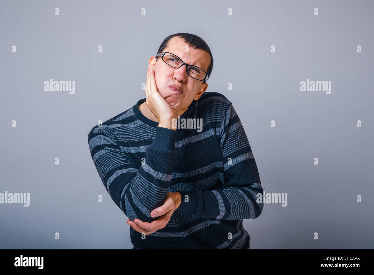 European-looking male put his hand to his cheek wrinkled his fac Stock ...