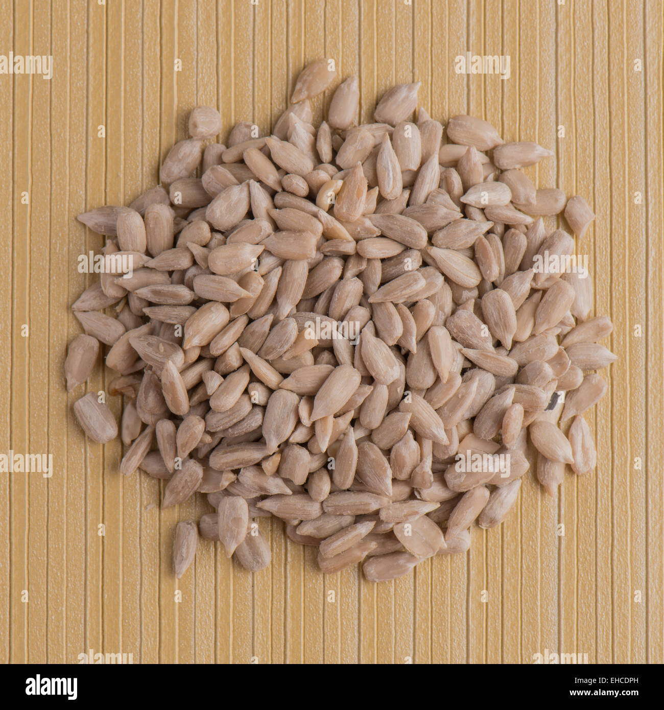 Top view of circle of shelled sunflower seeds against yellow vinyl ...