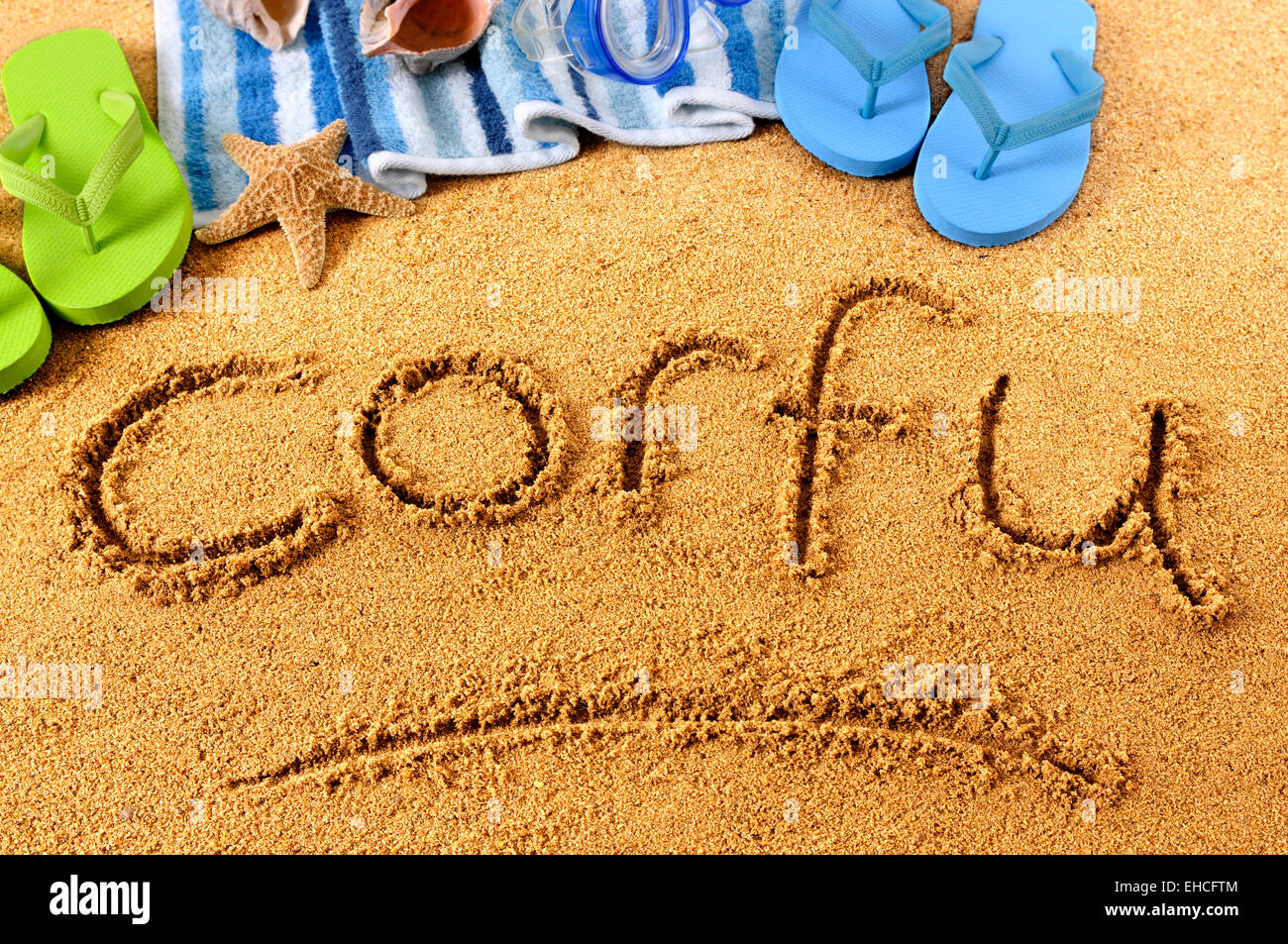 The word Corfu written on a sandy beach, with beach towel, starfish and ...