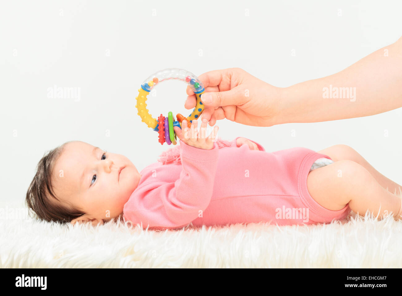 Mom giving a rattle her little baby girl. Copy space above Stock Photo ...