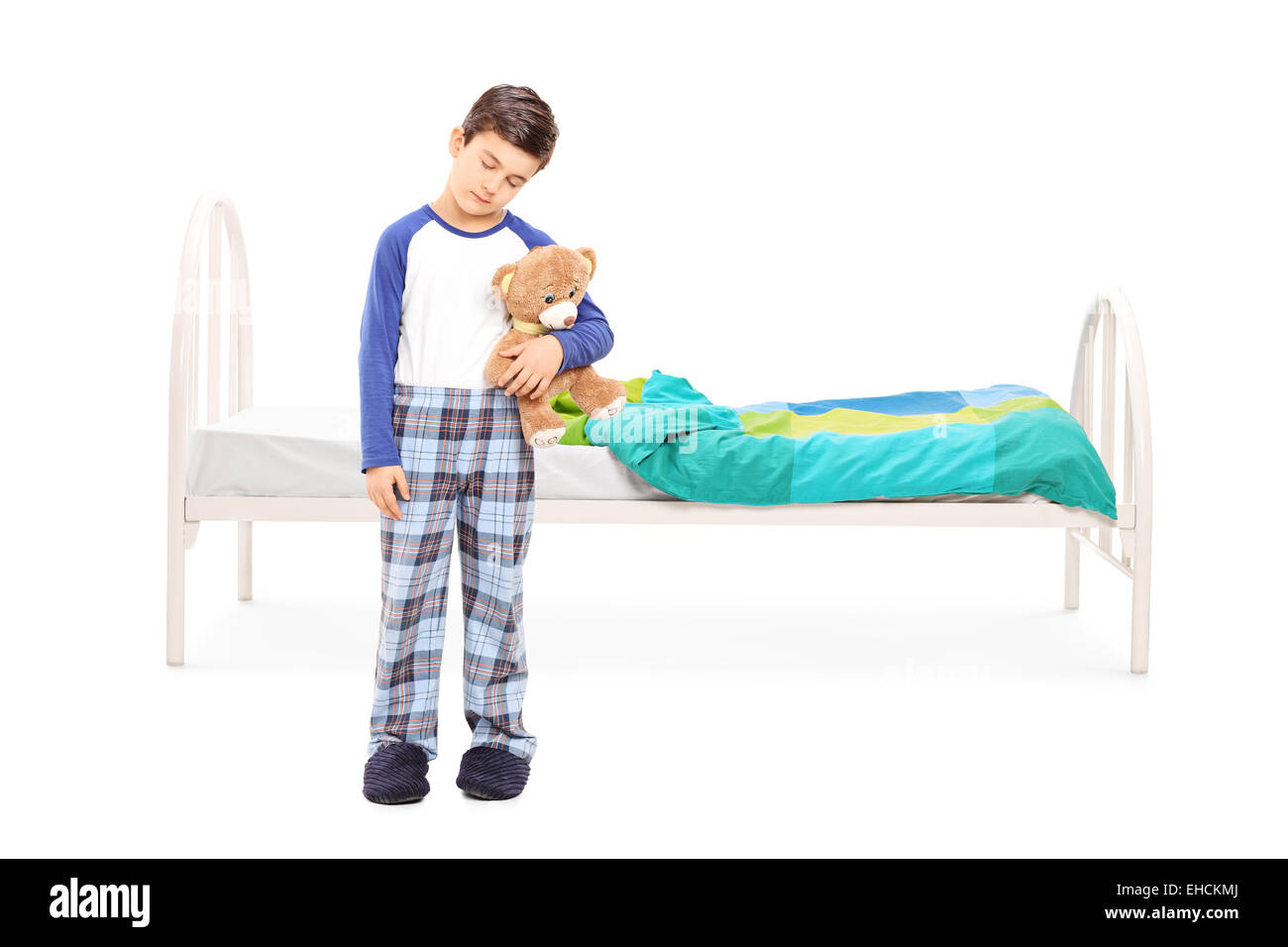 Full length portrait of a sleepy boy standing in front of a bed ...