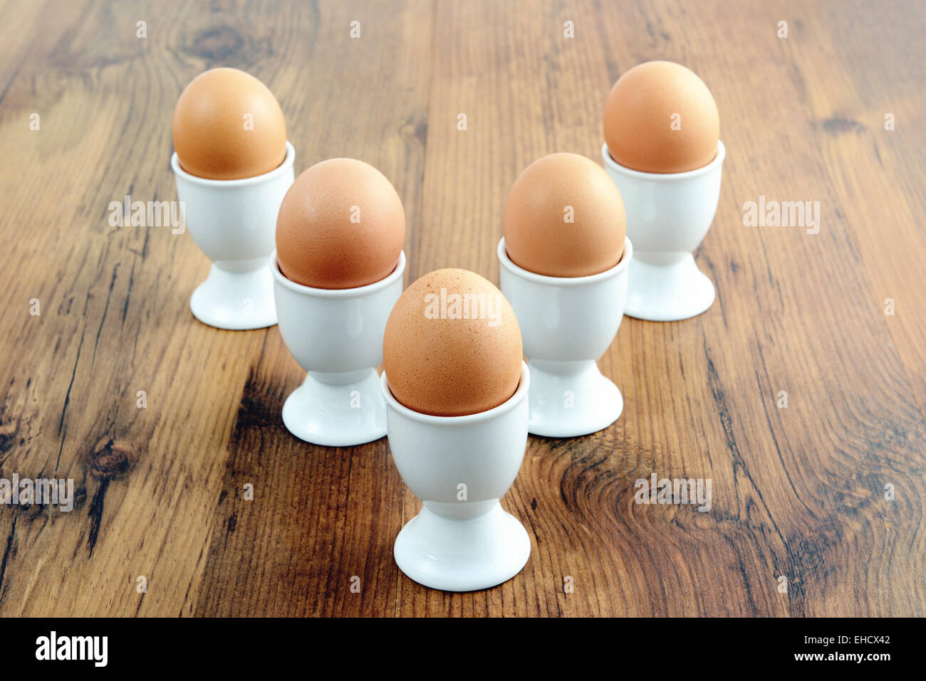 five egg cups with natural brown eggs in arrow shape on table Stock ...