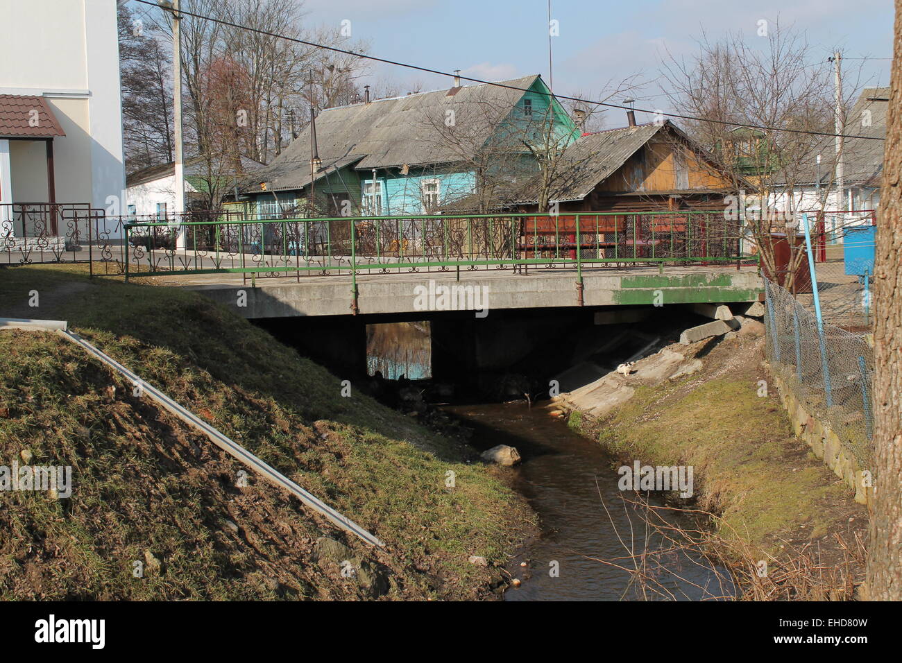 narrow stone bridge with green metal handle under flow of the creek ...