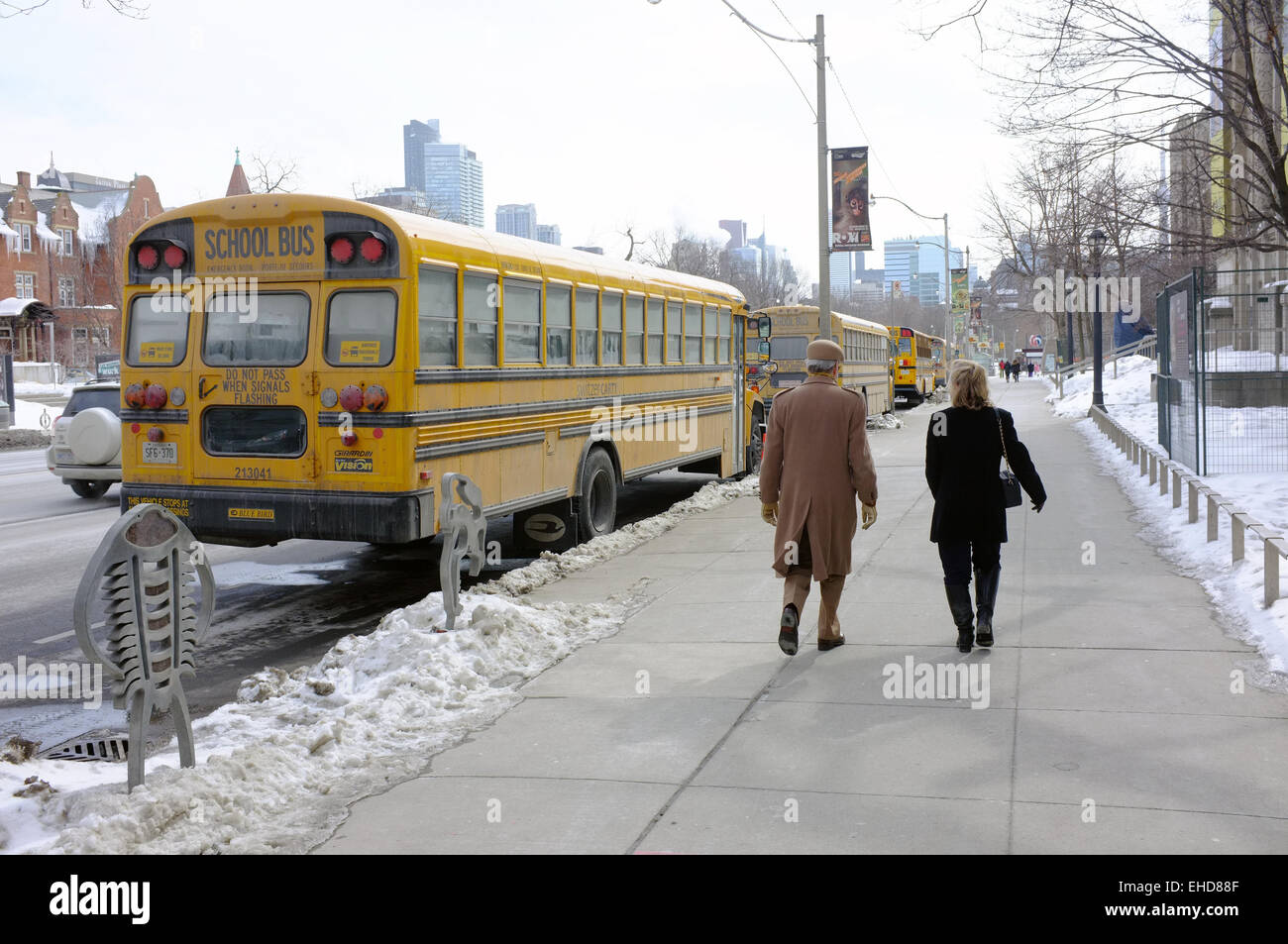 Pedestrians walk past yellow school buses in a snowy Toronto Stock ...