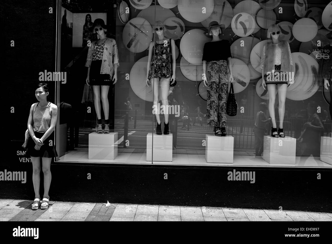 A woman stands next to fashion mannequins, along Queen's Road in ...