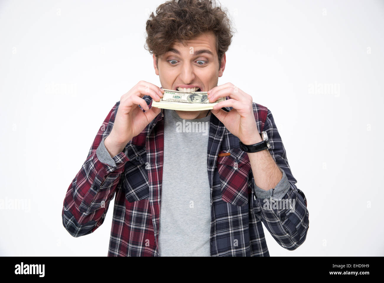 Young casual man biting money over gray background Stock Photo - Alamy