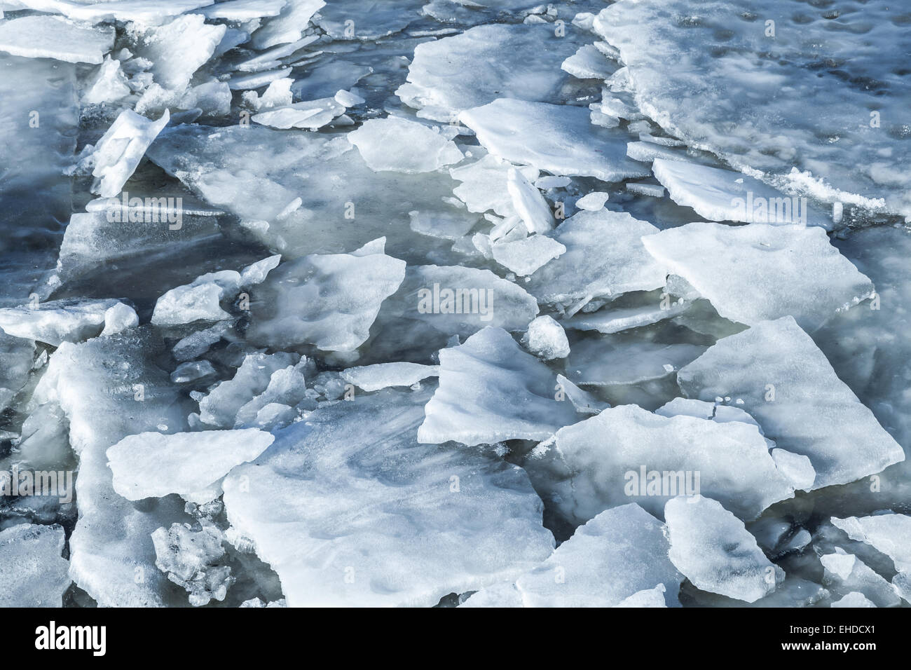 Big ice fragments covered with show on frozen river water. Dark blue ...
