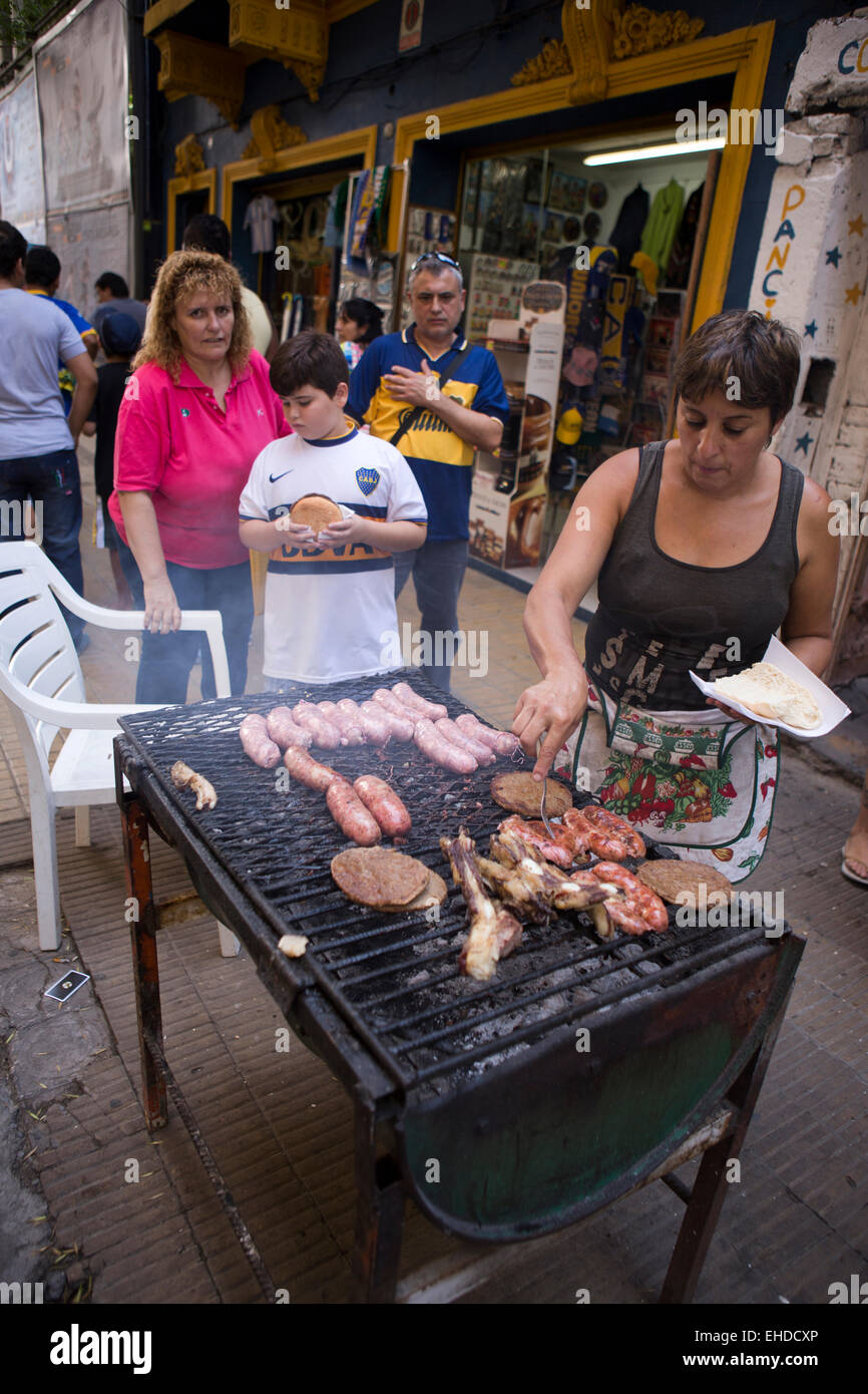 Argentina, Buenos Aires, La Boca, woman cooking meat on parilla ...