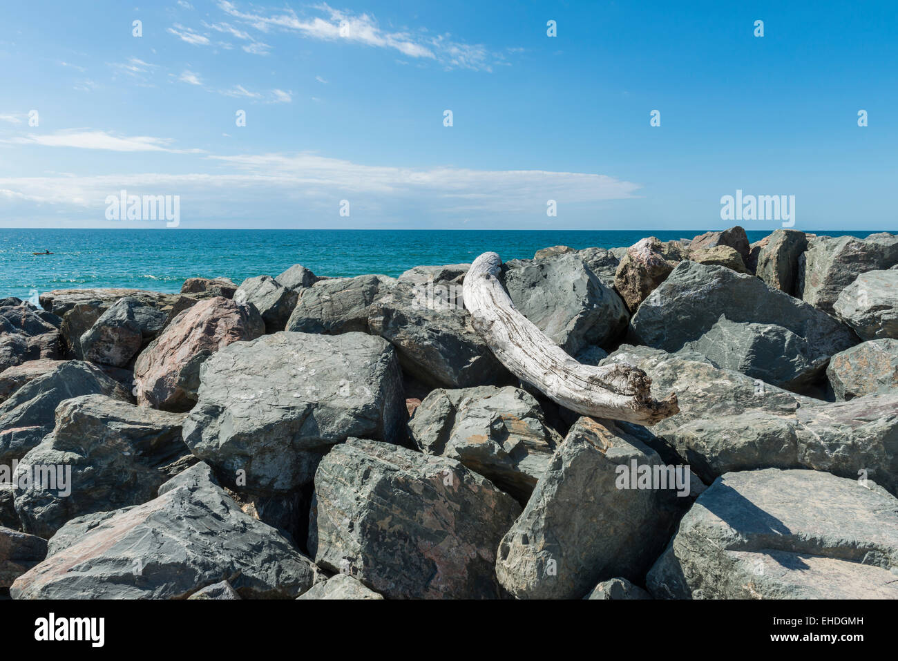Ocean with shore protection of rocks and a canoe on the water Stock ...